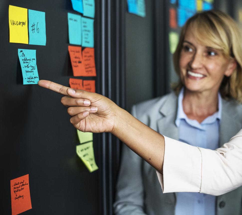 Free Stock Photo of A woman looks at sticky notes on the project board ...