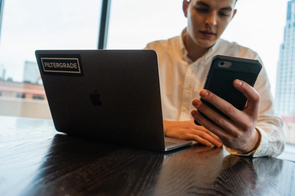 Free Stock Photo of Young man using mobile phone while working on ...