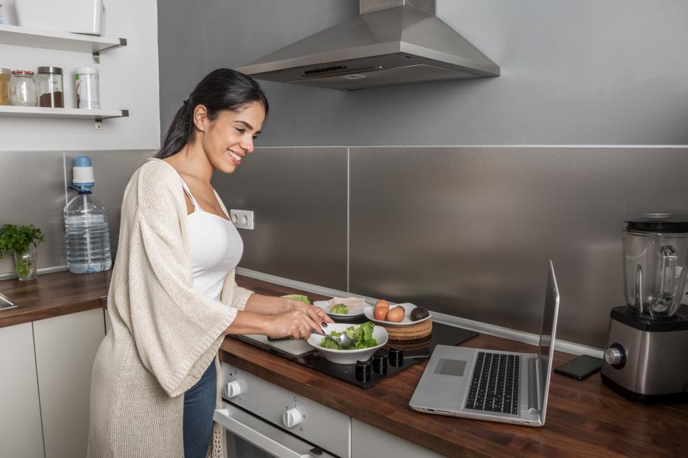 Free Stock Photo of Smiling woman cooking salad and watching video on ...