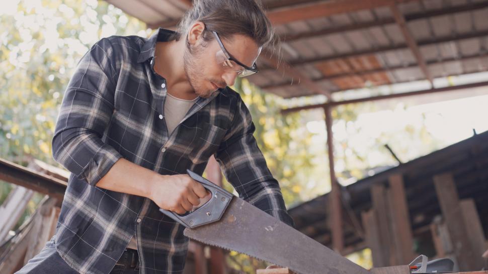 Free Stock Photo of Male carpenter using hand saw for cutting timber ...