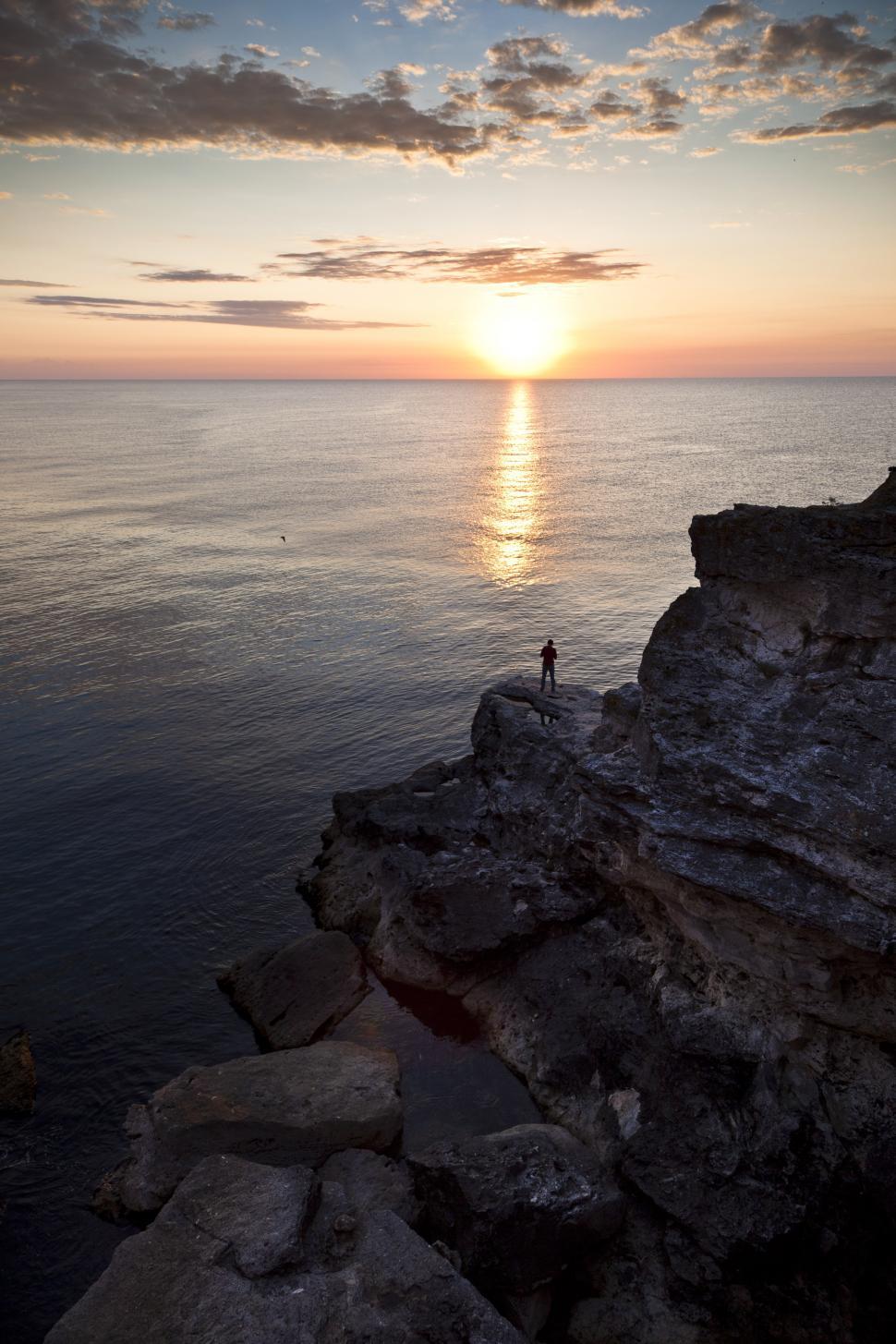 Free Stock Photo of A person standing on a cliff overlooking a body of ...