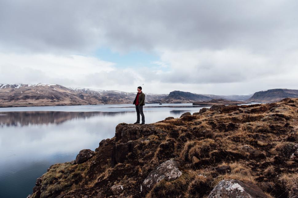 Free Stock Photo of A man standing on a rocky cliff overlooking a body ...