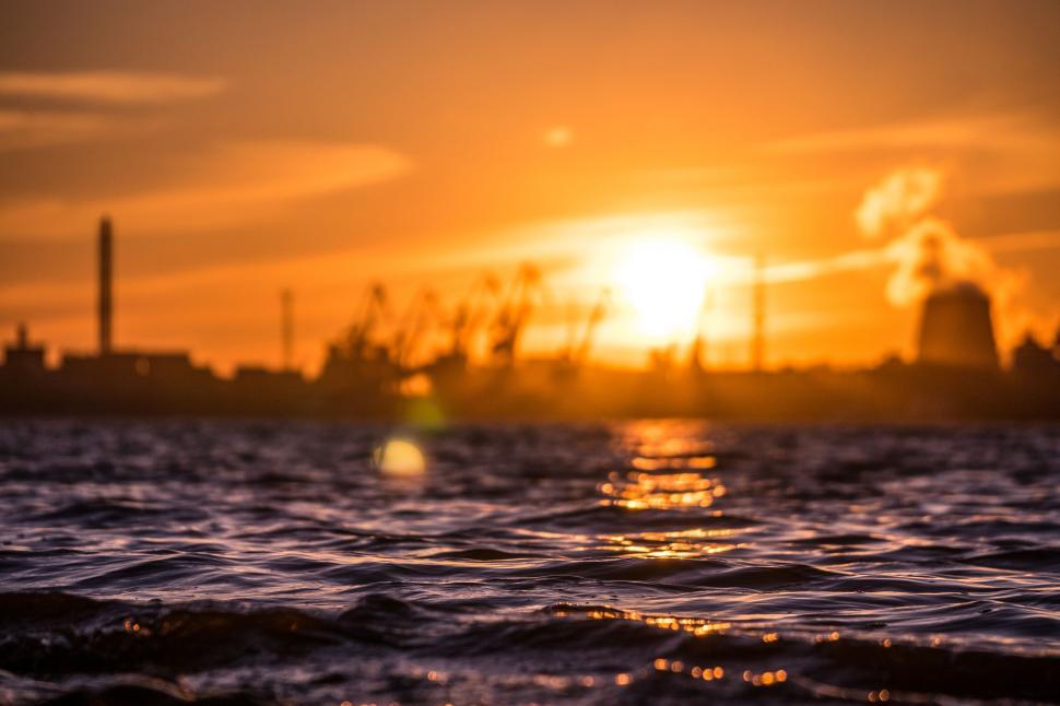 Free Stock Photo of A sunset over water with cranes in the background ...