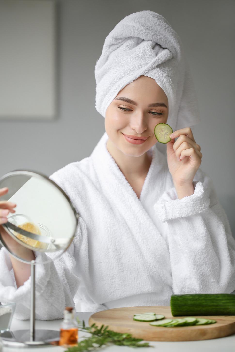Free Stock Photo of A woman in a white robe holding a cucumber slice on ...