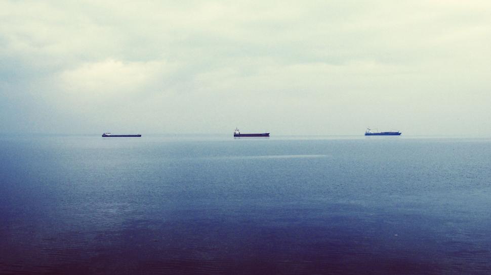 Free Stock Photo of Three distant cargo ships float on the vast calm ...