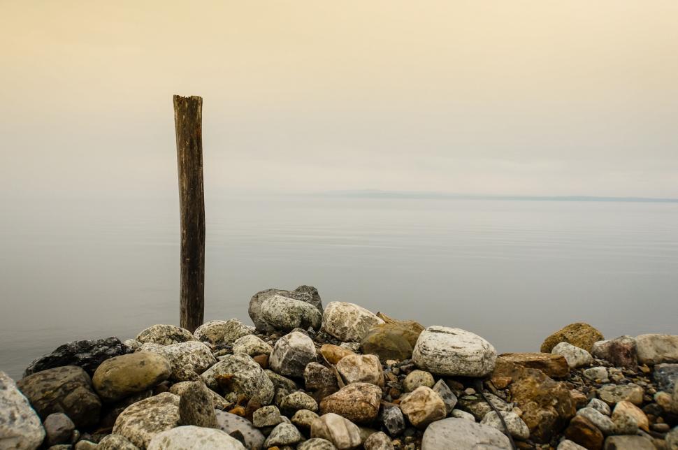 Free Stock Photo of Tranquil lakeside with rocks and single standing ...
