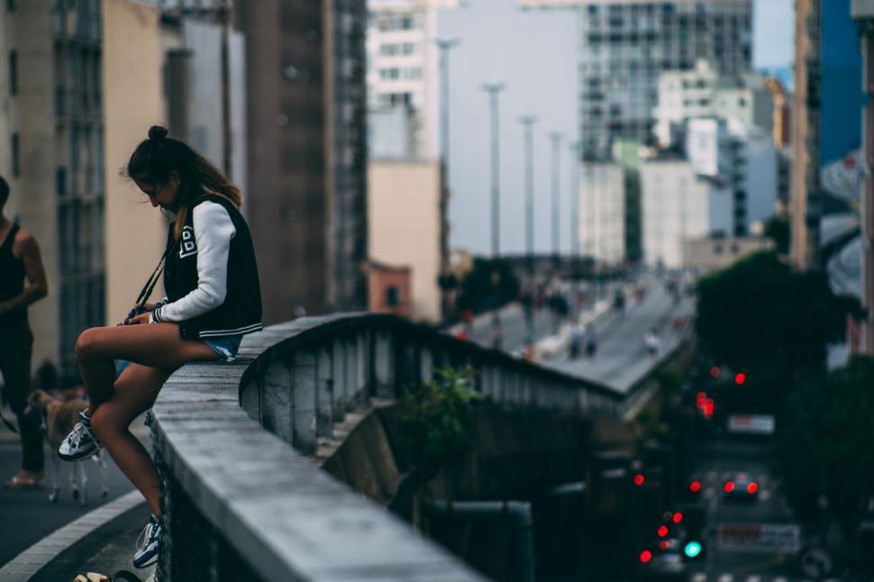 Free Stock Photo of Person sitting on ledge overlooking bustling city ...
