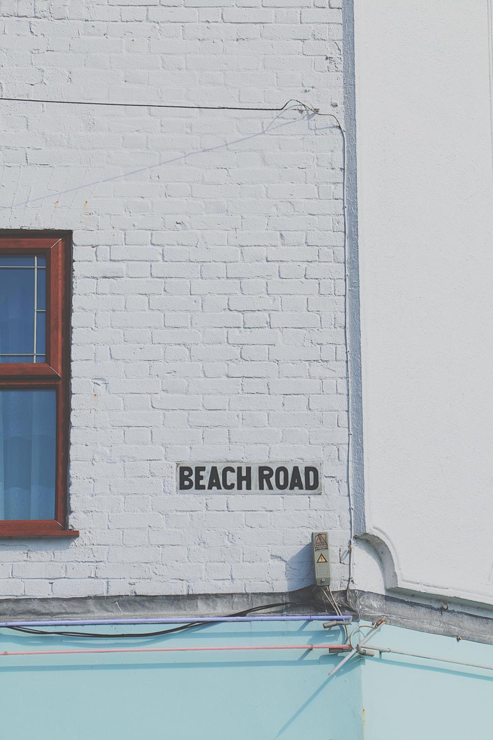 Free Stock Photo of Beach Road sign on a white brick wall with a window ...