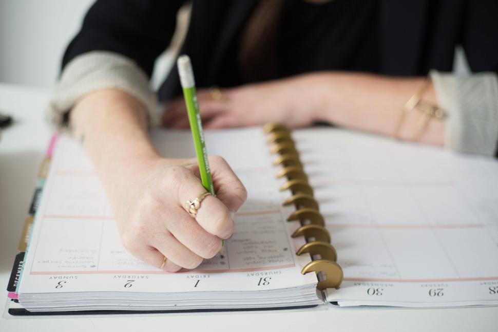 Free Stock Photo of Person writing plans in a spiral-bound planner with ...