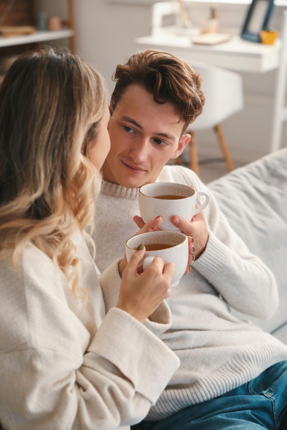 Free Stock Photo of Couple sharing coffee on couch enjoying a relaxed ...