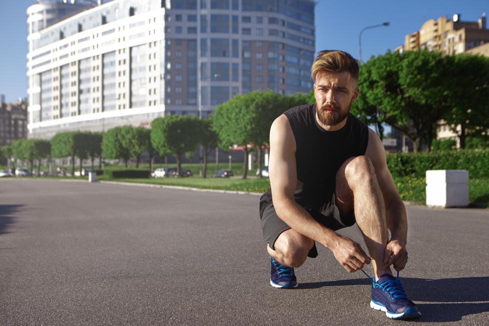 Free Stock Photo of Fashionable young unshaven male runner lacing up ...