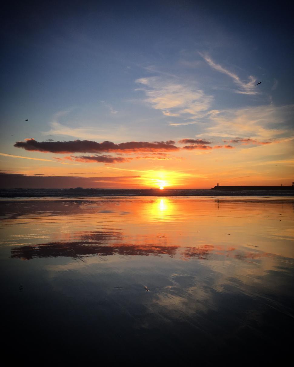 Free Stock Photo of Stunning sunset reflecting on calm beach waters ...