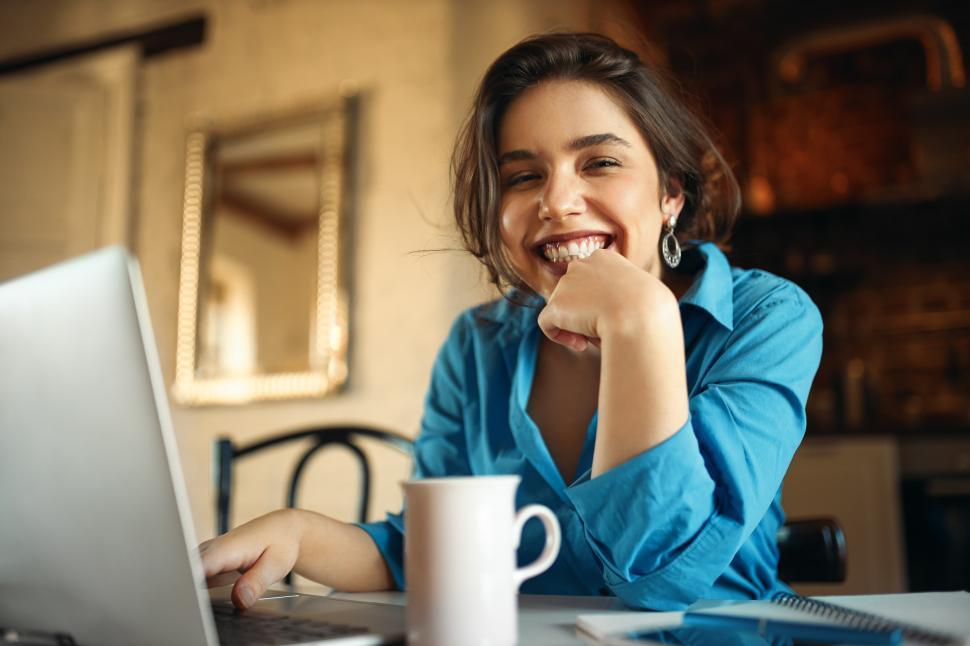 Free Stock Photo of Cheerful attractive young woman enjoying distant work, sitting at desk using ...