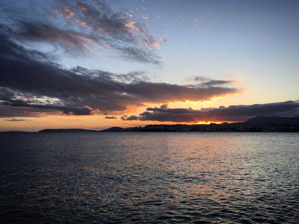 Free Stock Photo of Sunset over a calm sea with clouds and distant land ...