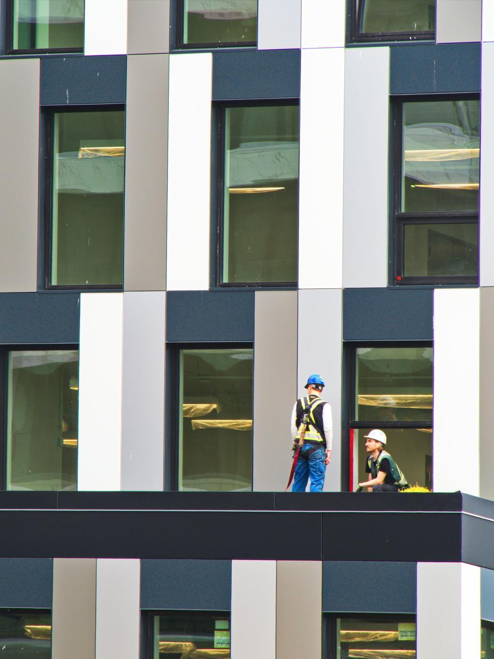 Free Stock Photo of Two workers stand on roof of modern building with ...