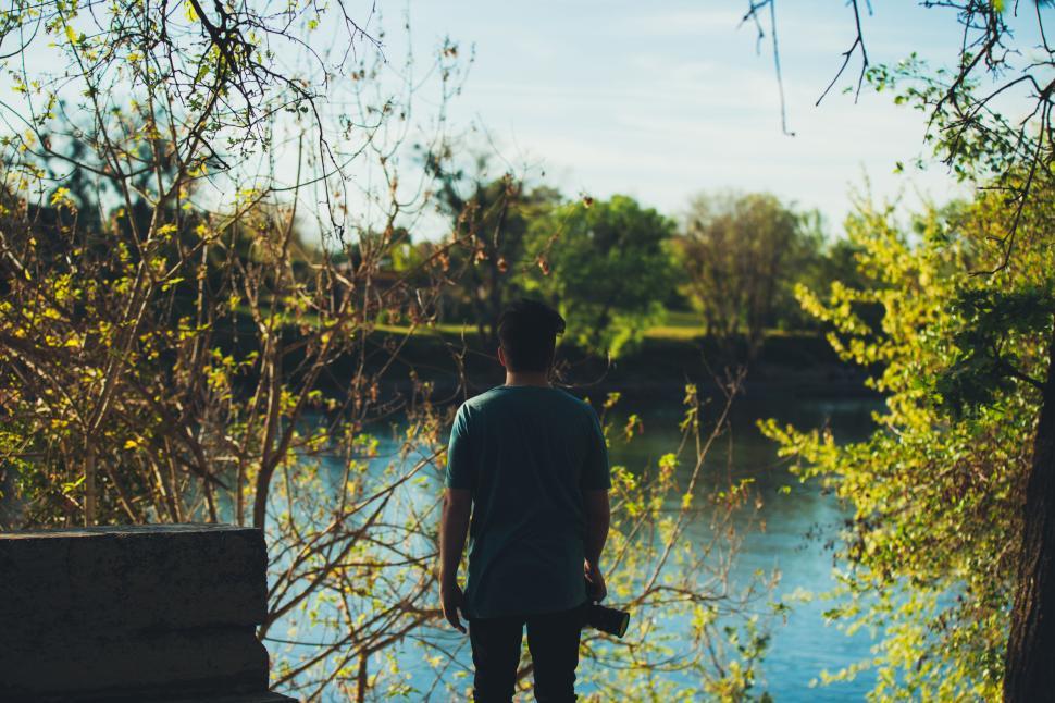 Free Stock Photo of Person standing by a serene river surrounded by ...