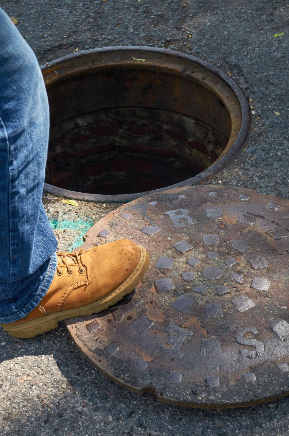Free Stock Photo of Person standing by an open manhole on a paved ...