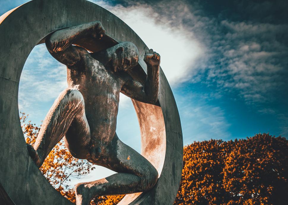 Free Stock Photo of Statue of a man pushing against a circular frame ...