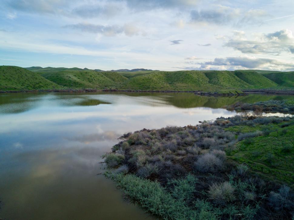 Free Stock Photo of Lush green hills surrounding a calm reflective lake ...
