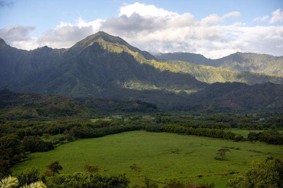 Free Stock Photo of Wide green field surrounded by tall mountainous ...