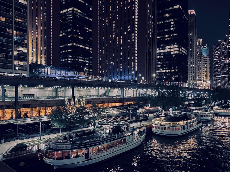Free Stock Photo of Evening stroll along the Chicago Riverwalk with boats illuminated by city ...
