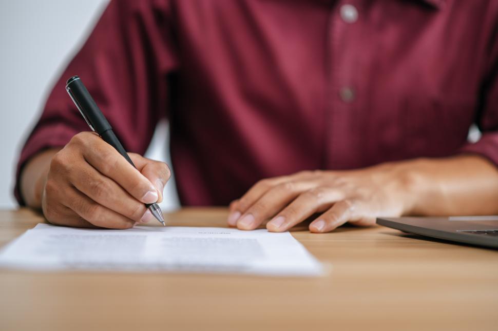 Free Stock Photo of Male employee signing documents to approve work ...