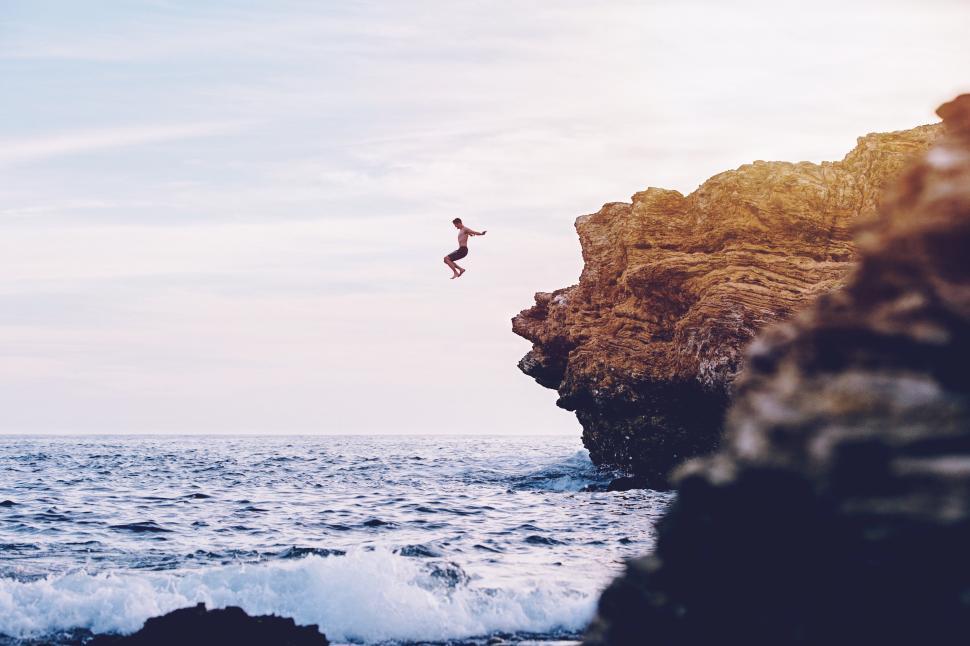 Free Stock Photo of Person jumping off a cliff into the ocean at sunset ...
